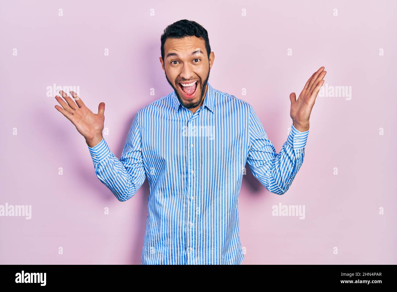 Hispanic man with beard wearing casual blue shirt celebrating crazy and ...