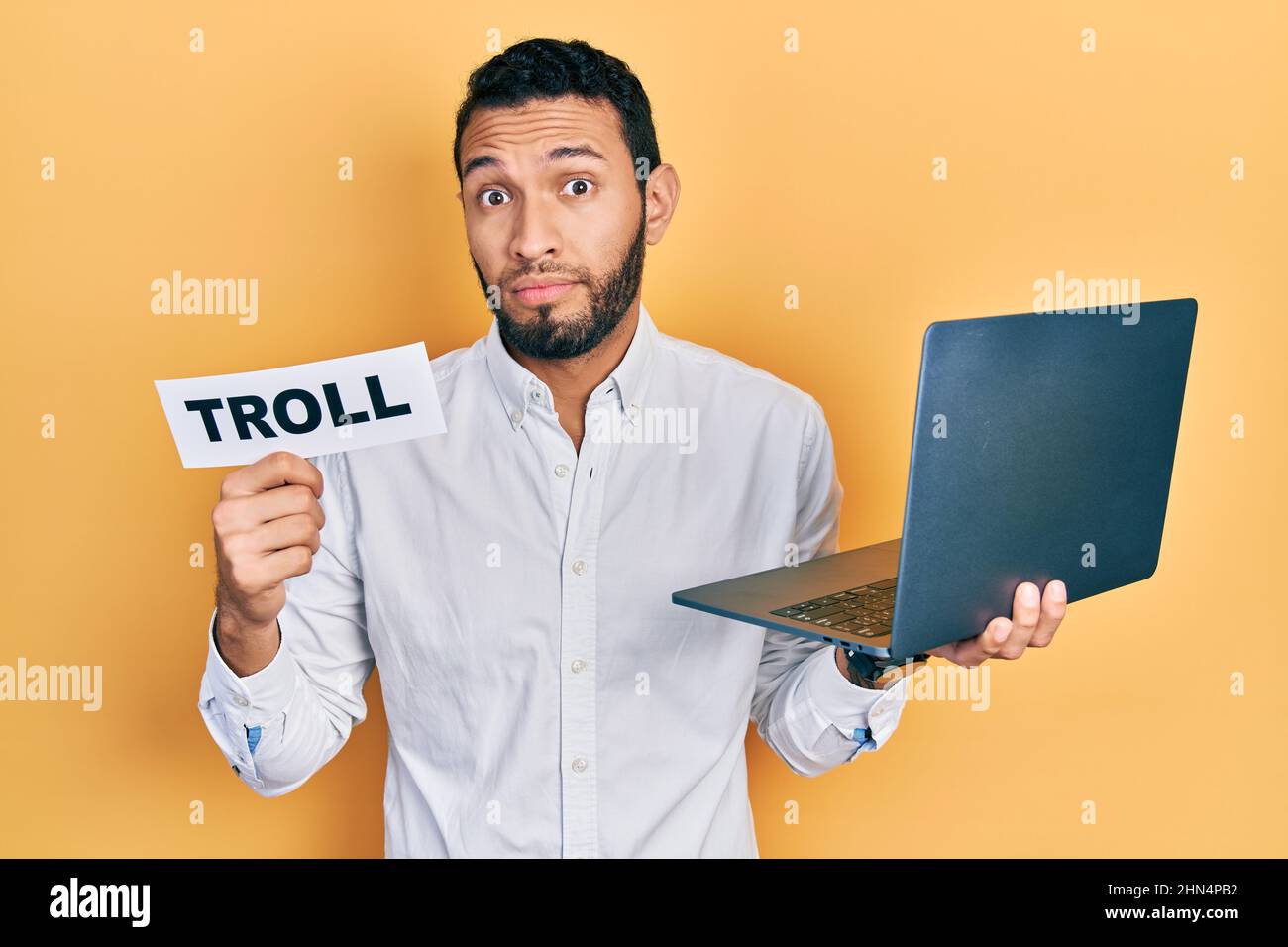 Hispanic man with beard working using computer laptop holding banner ...