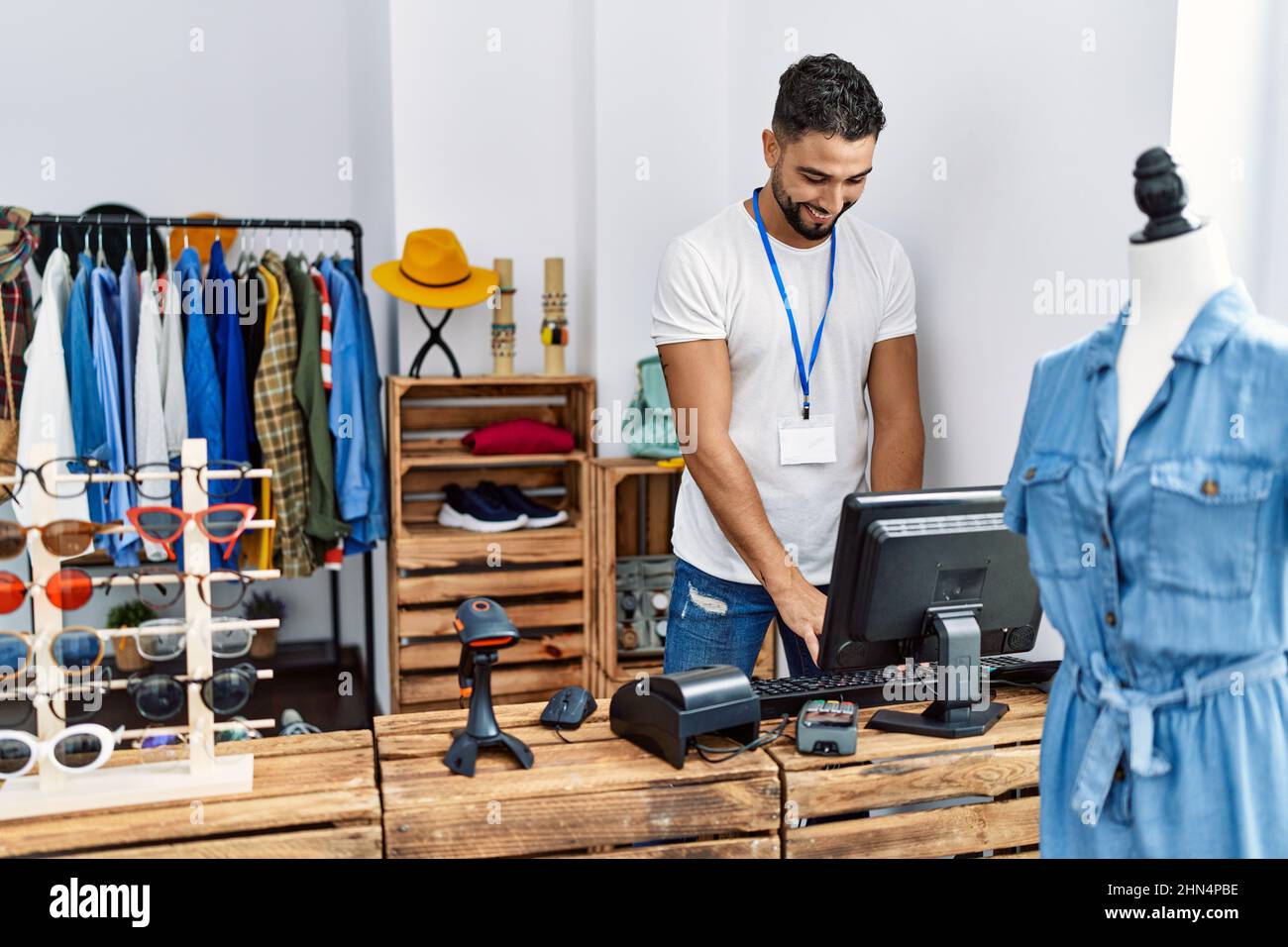 Young arab man shopkeeper smiling confident working at clothing store ...