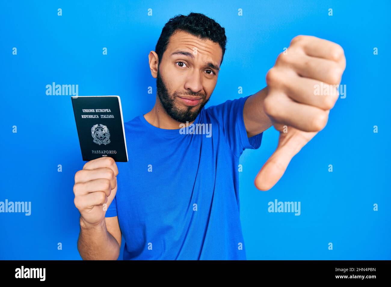 Hispanic man with beard holding italy passport looking unhappy and ...