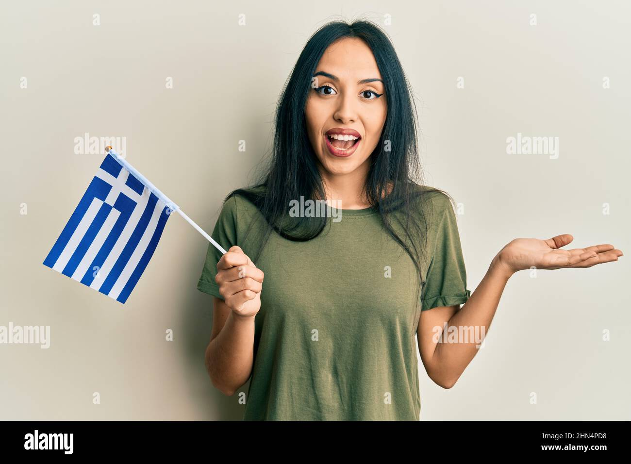 Young hispanic girl holding greece flag celebrating achievement with ...