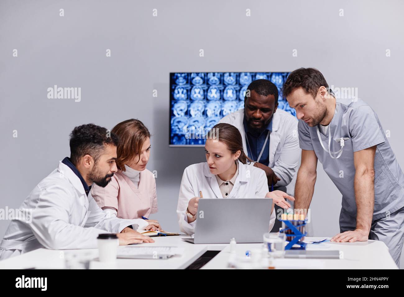 Group of young colleagues listening to female clinician explanation of ...