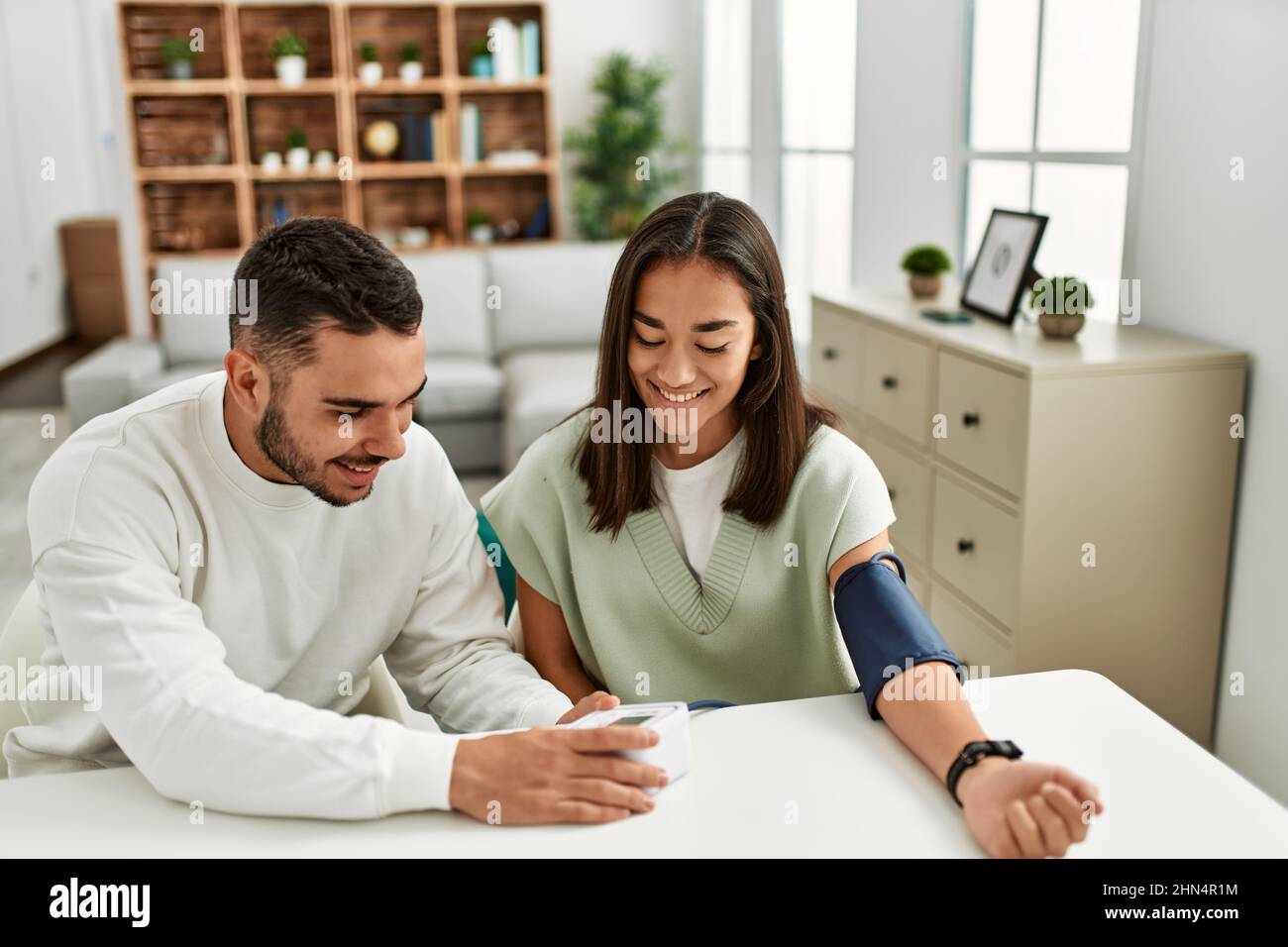 Young latin couple smiling happy measuring blood pressure using ...