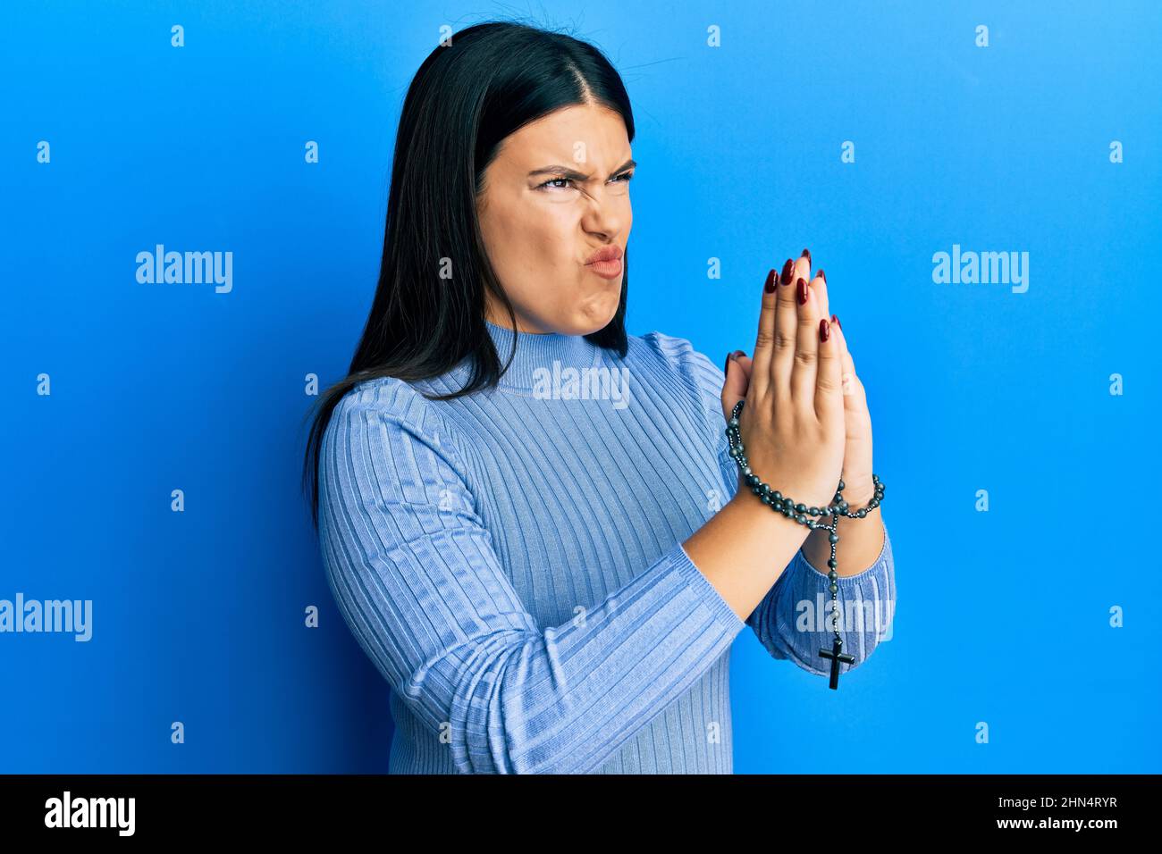 Beautiful brunette woman praying holding catholic rosary skeptic and ...