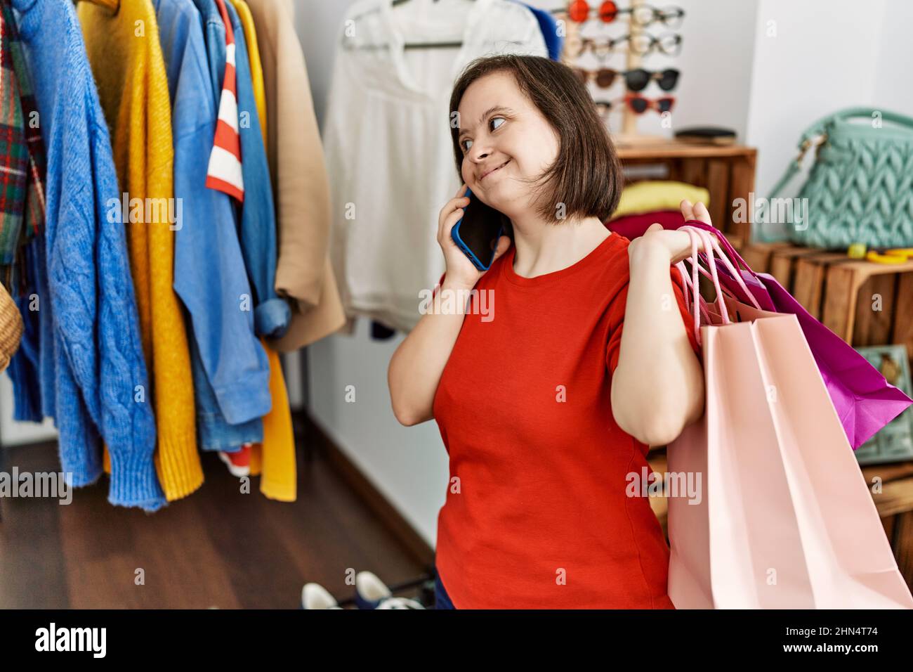 Brunette woman with down syndrome holding shopping bags speaking on the ...