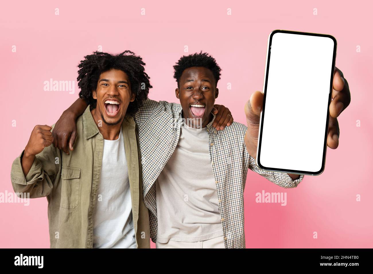 Overjoyed two black male friends showing cellphone with white blank ...