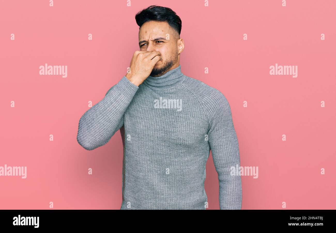 Young arab man wearing casual clothes smelling something stinky and ...