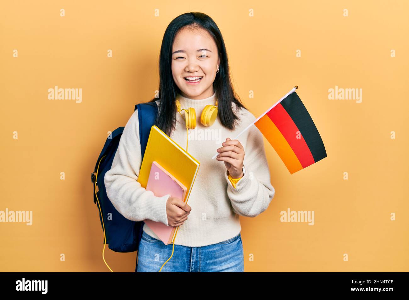 Young chinese girl exchange student holding germany flag smiling and ...