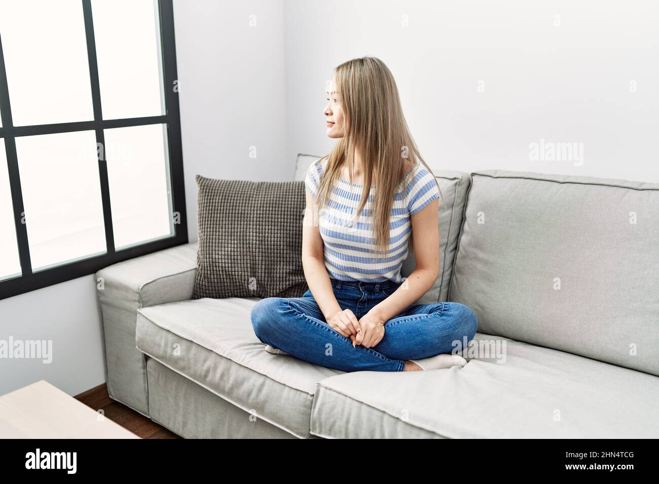 Asian young woman sitting on the sofa at home looking to side, relax ...