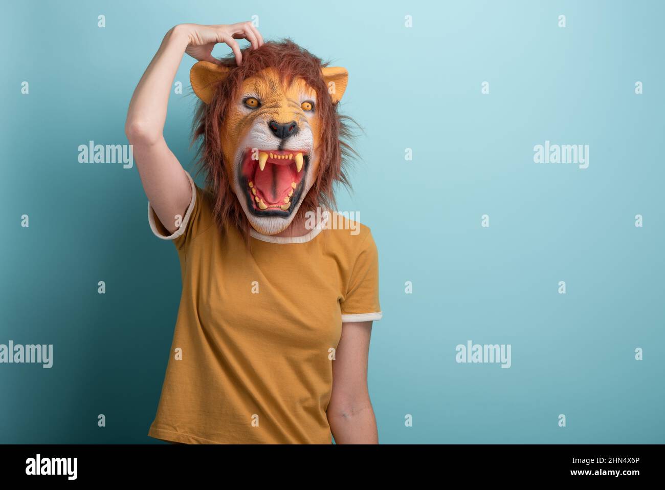 Young woman in lion mask thinking, scratching her head, isolated on ...