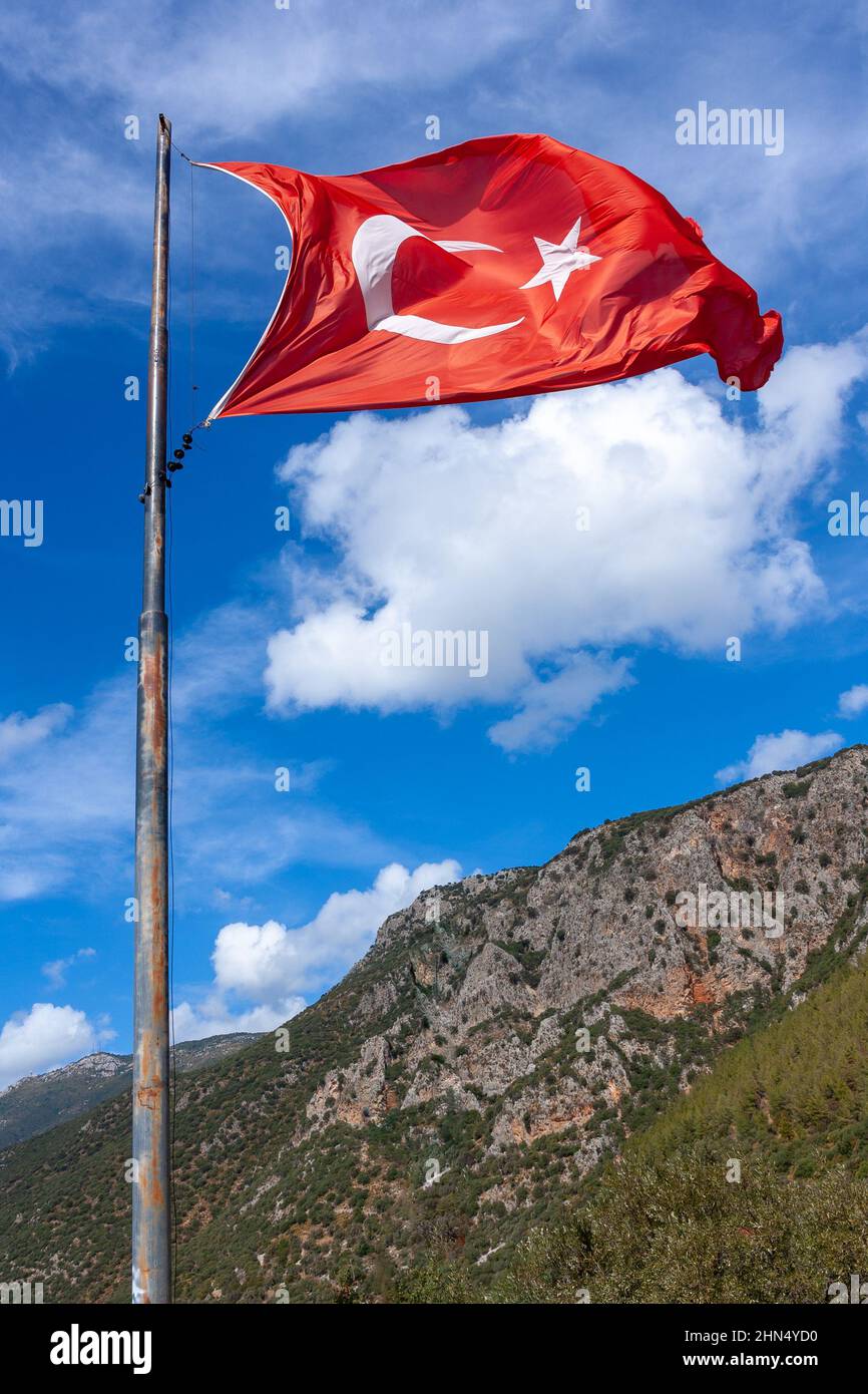 Waving Turkish national flag on flagpole against backdrop of mountains ...