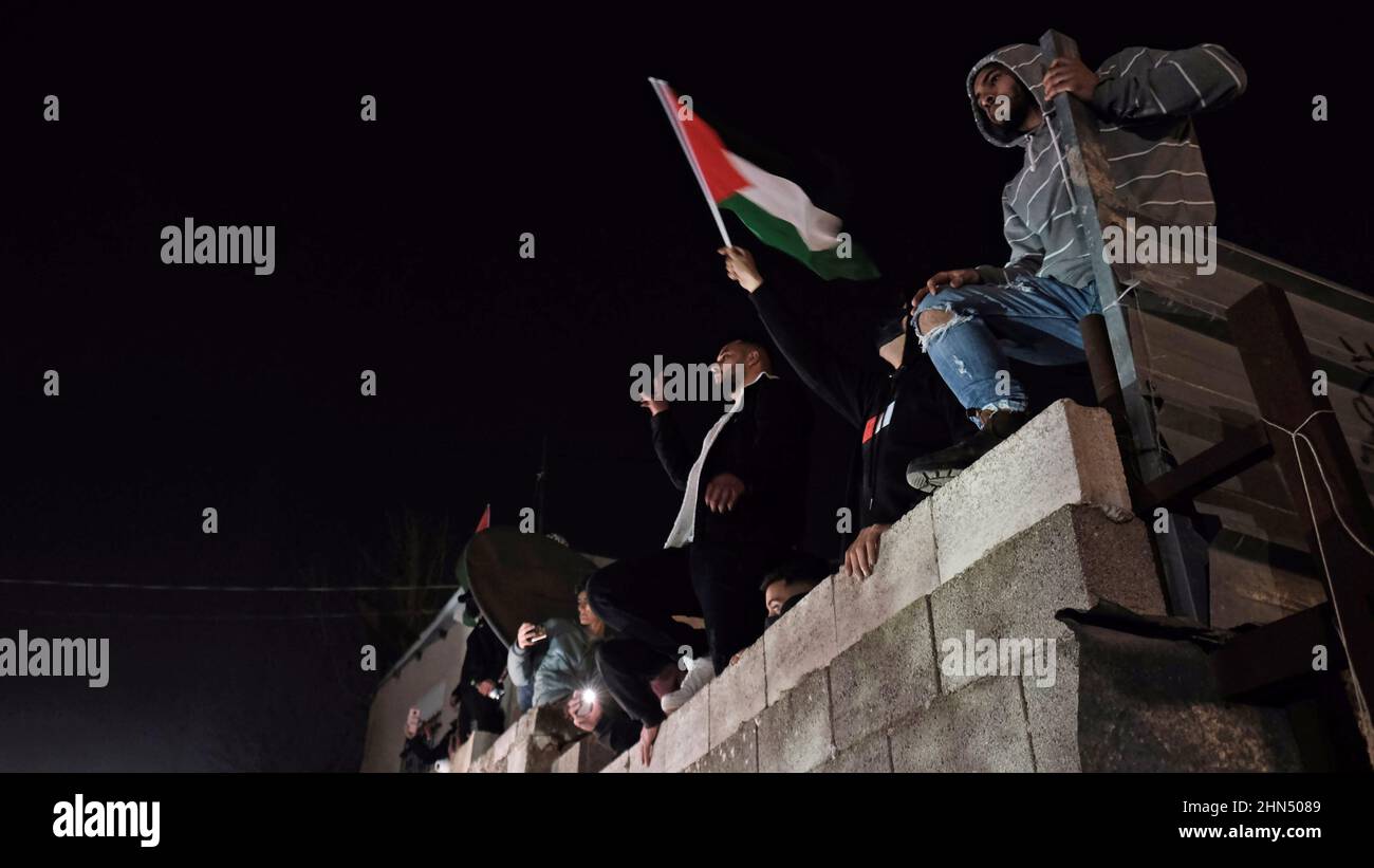 Palestinians hold up the victory sign and the Palestinian flag as they ...