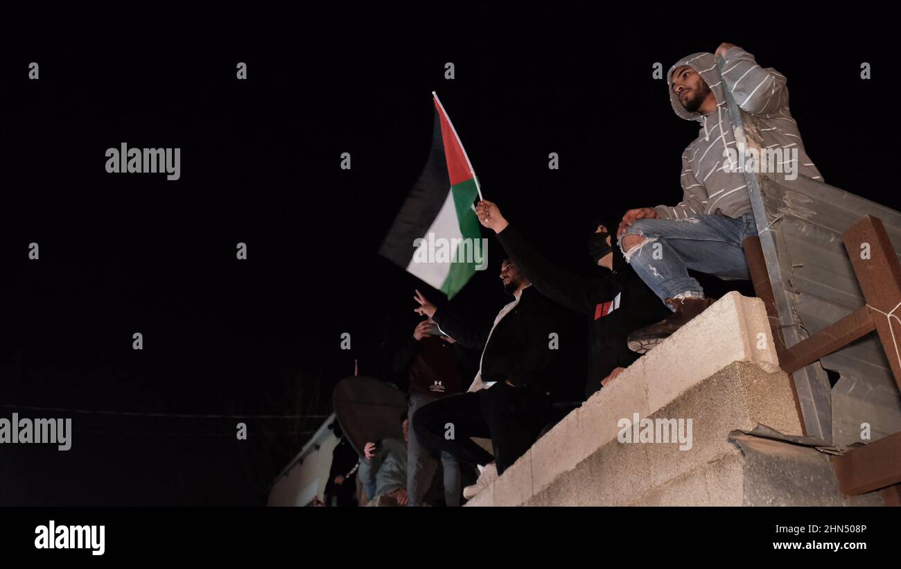 Palestinians hold up the victory sign and the Palestinian flag as they ...