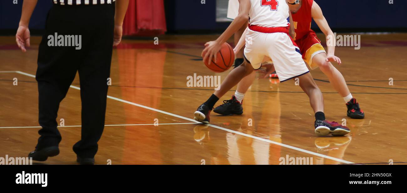 Rear view of a high school bay basketball player dribbling the ball ...