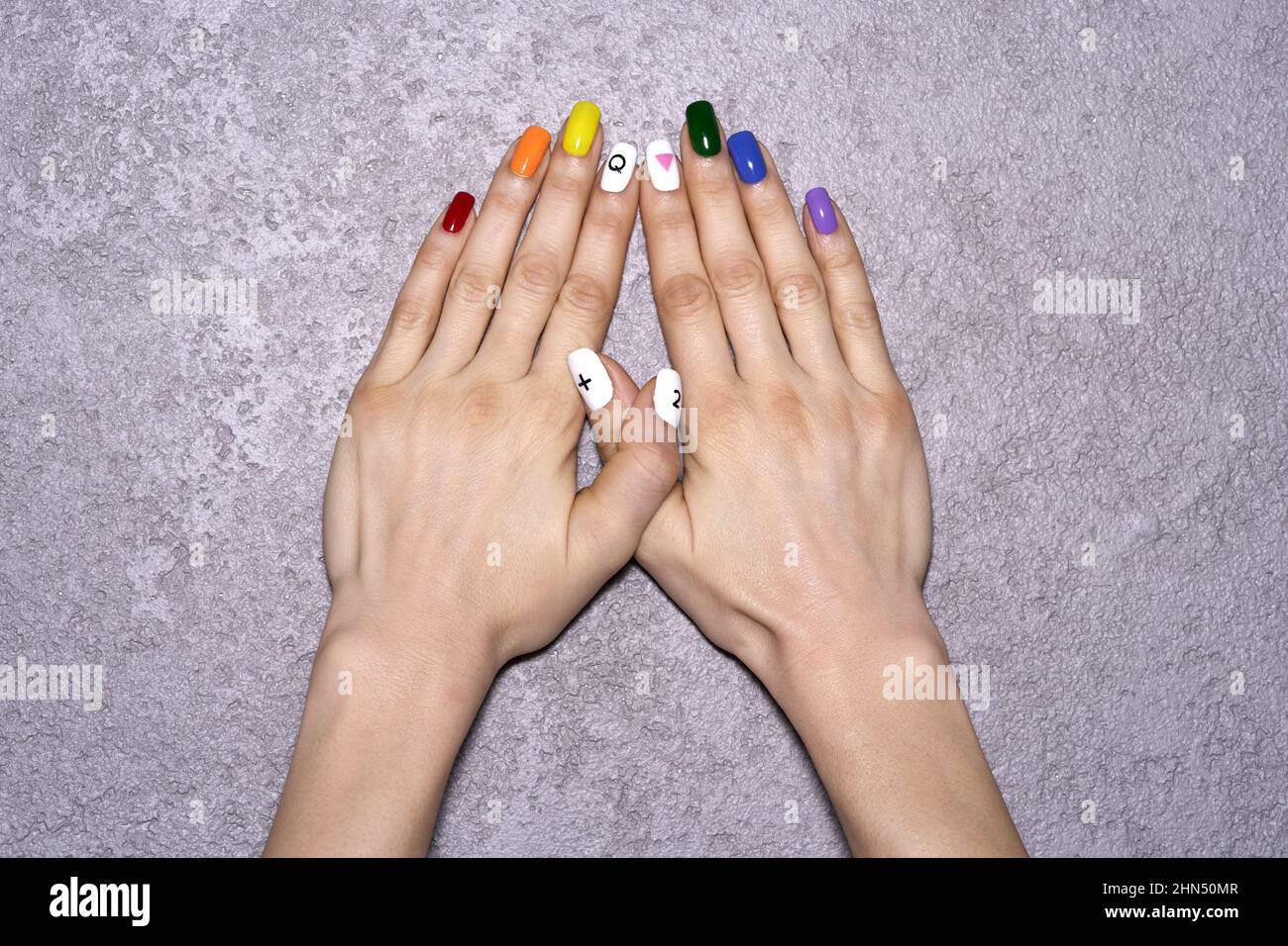 Hands with LGBT rainbow flag and rose triangle manicure. Symbol of ...