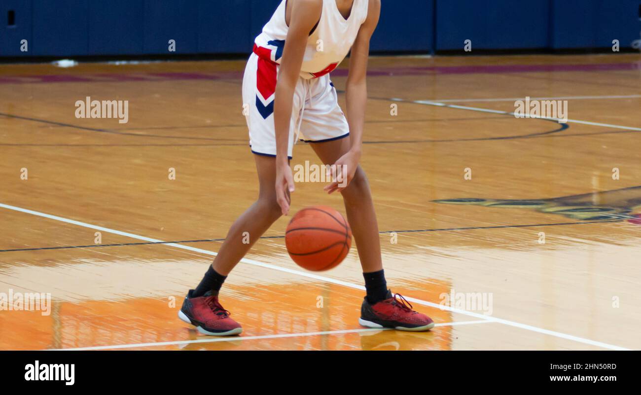Front view of a high school basketball player dribbling the ball at the ...