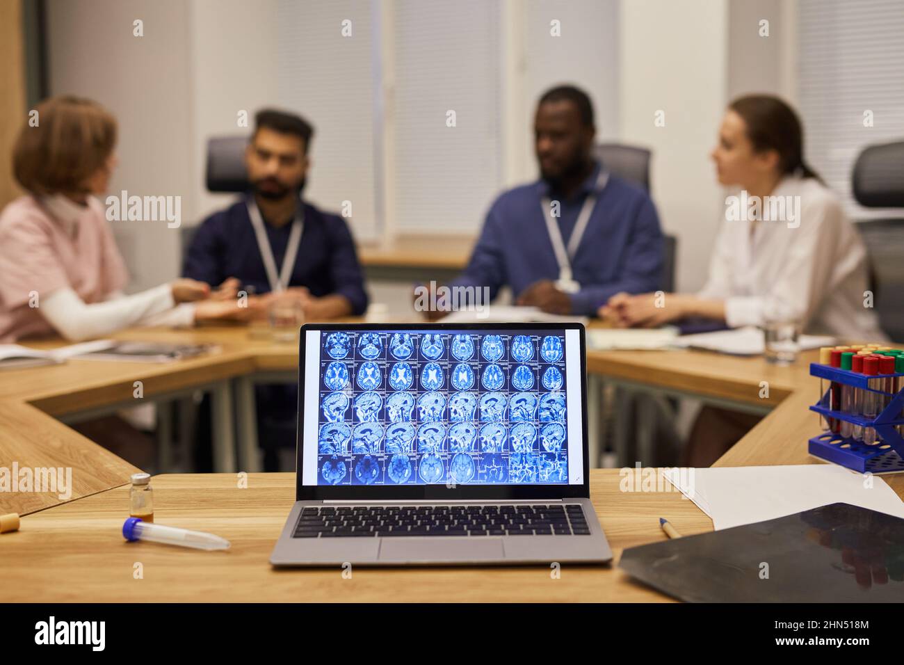 Laptop screen with brain scan and four experts on background discussing ...