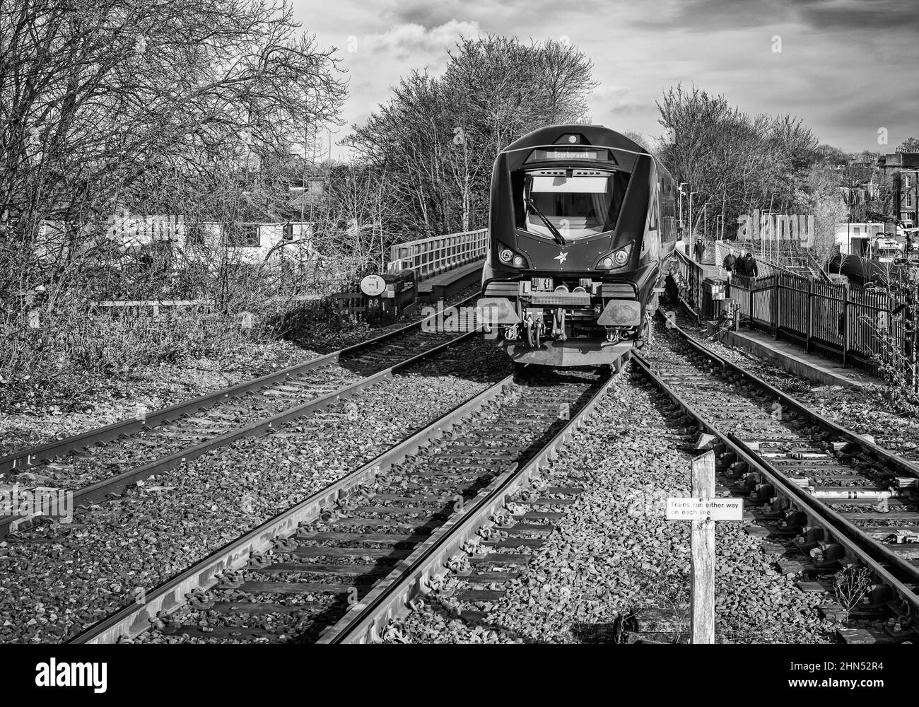 A train crosses over a railway bridge. A footbridge is to one side and ...