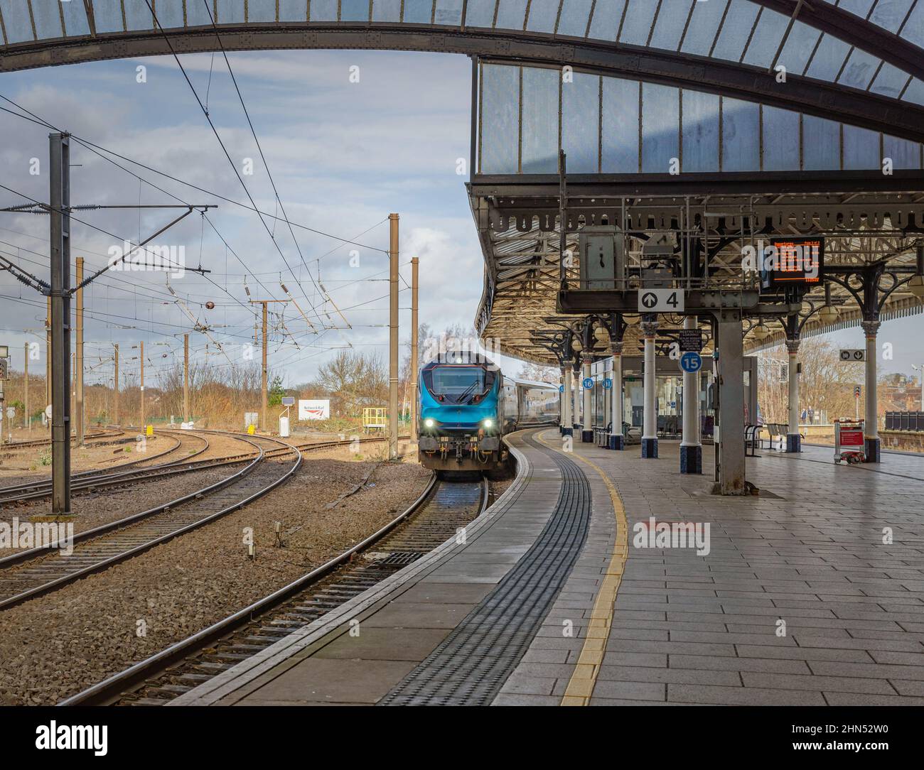 A train approaches a station beside a historic canopy with columns. An ...