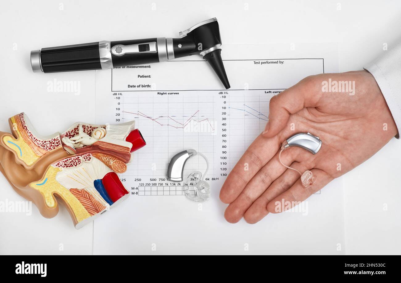 Hearing aid in doctor hand near patient audiogram test , otoscope and ...