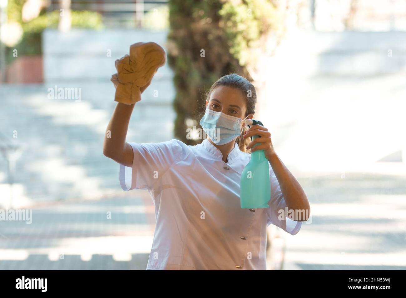 Cleaning lady using a face mask while cleaning the window Stock Photo ...