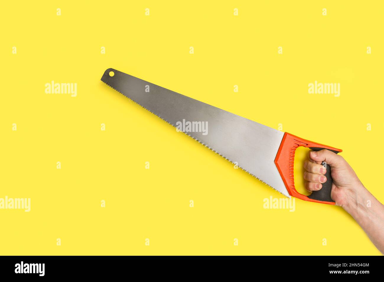 Man hand holding a saw on a yellow background with copy space Stock ...