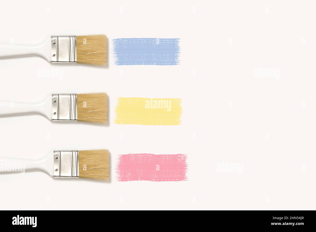 Three paintbrushes with pastel colored painting trace on a white ...