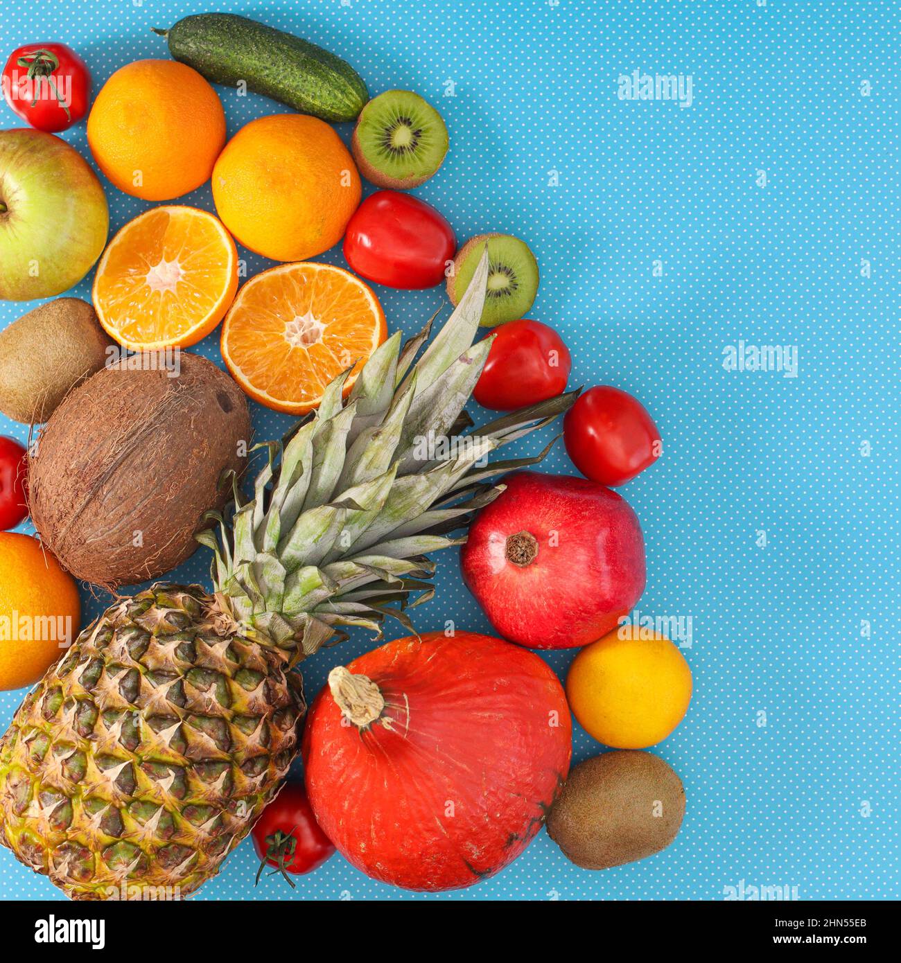 Exotic fruits and vegetables arrangement on vibrant blue background. Flat lay fresh organic food ...