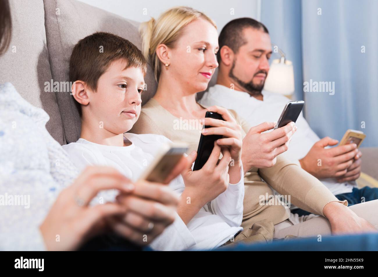 Parents and son using phones at home Stock Photo - Alamy
