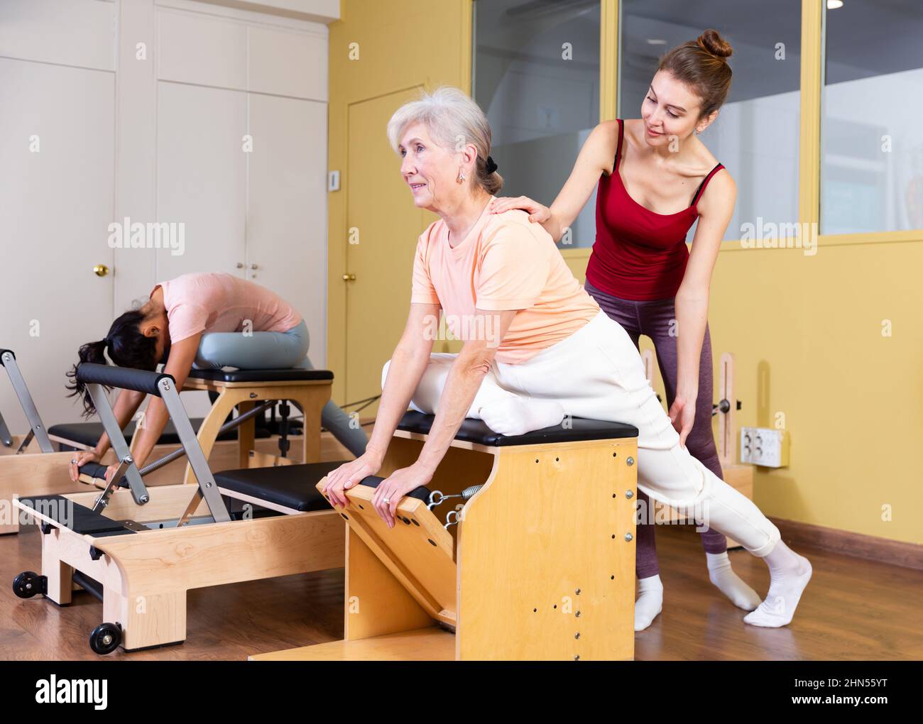 Mature woman trains on a combined chair with instructor Stock Photo - Alamy