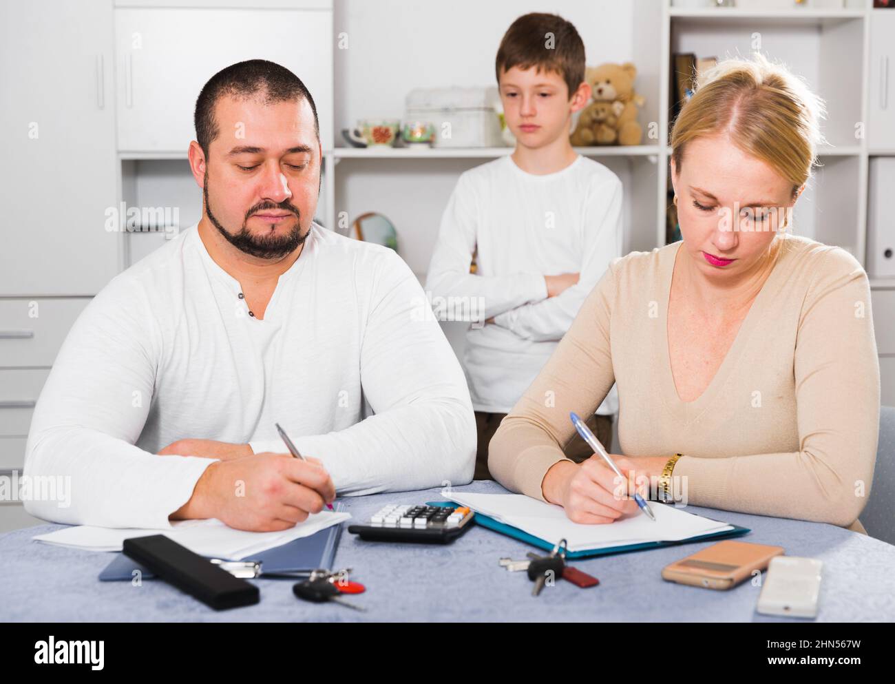 Parents calculating family budget while son standing behind Stock Photo ...