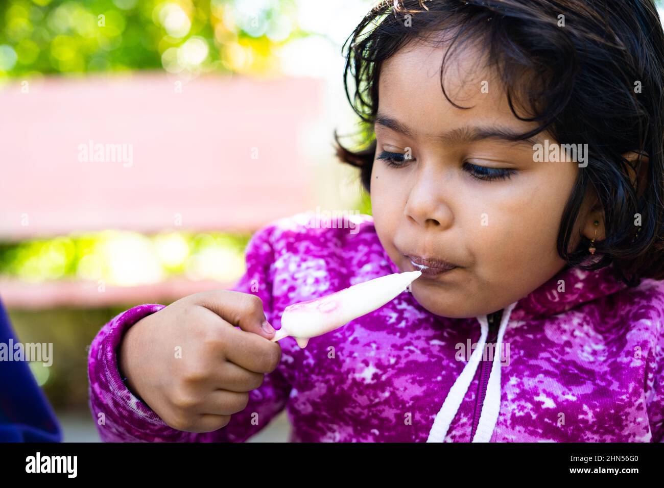 Cute little girl kid busy eating ice cream candy during winter at park ...