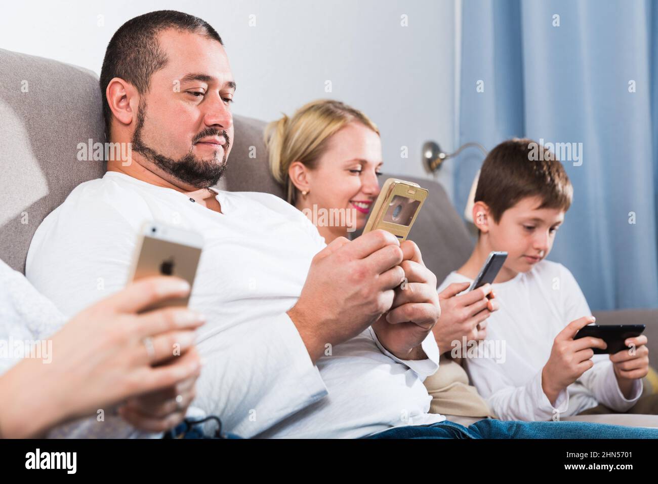Parents and son using phones at home Stock Photo - Alamy
