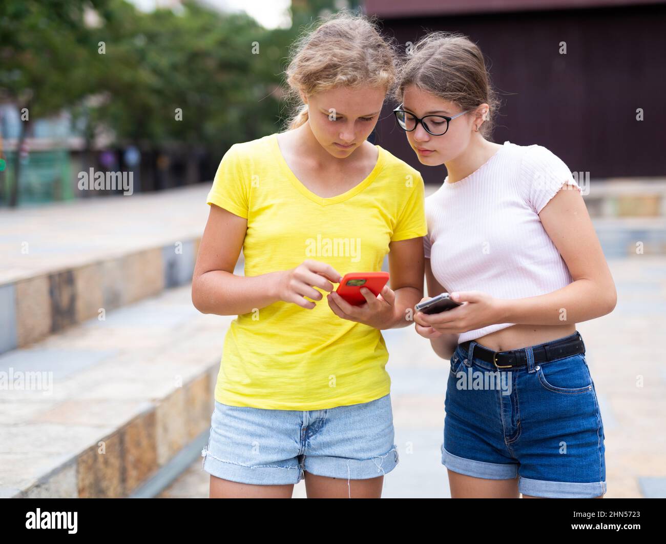 Two teenagers chatting on their smartphone Stock Photo - Alamy