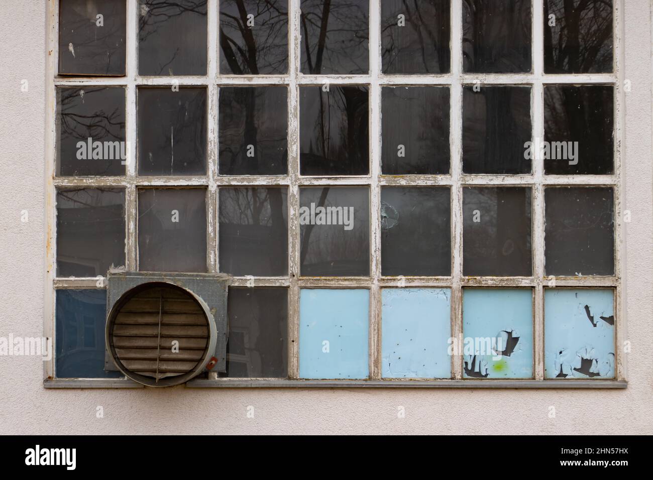 Old and broken industrial factory window with built in ventilation fan ...