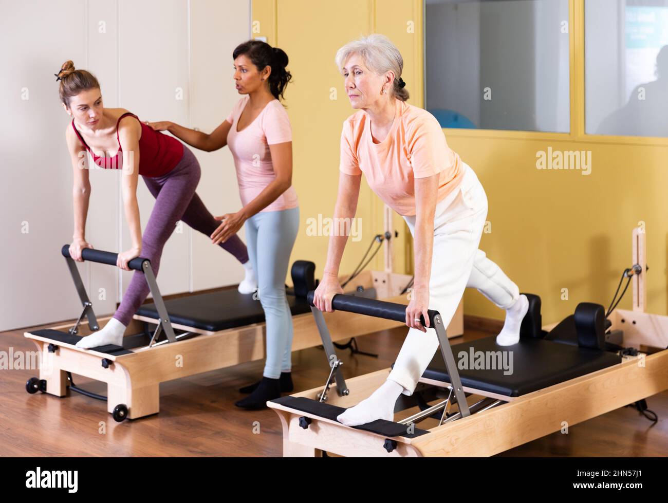 Two active women perform an exercise using a reformer bed Stock Photo ...