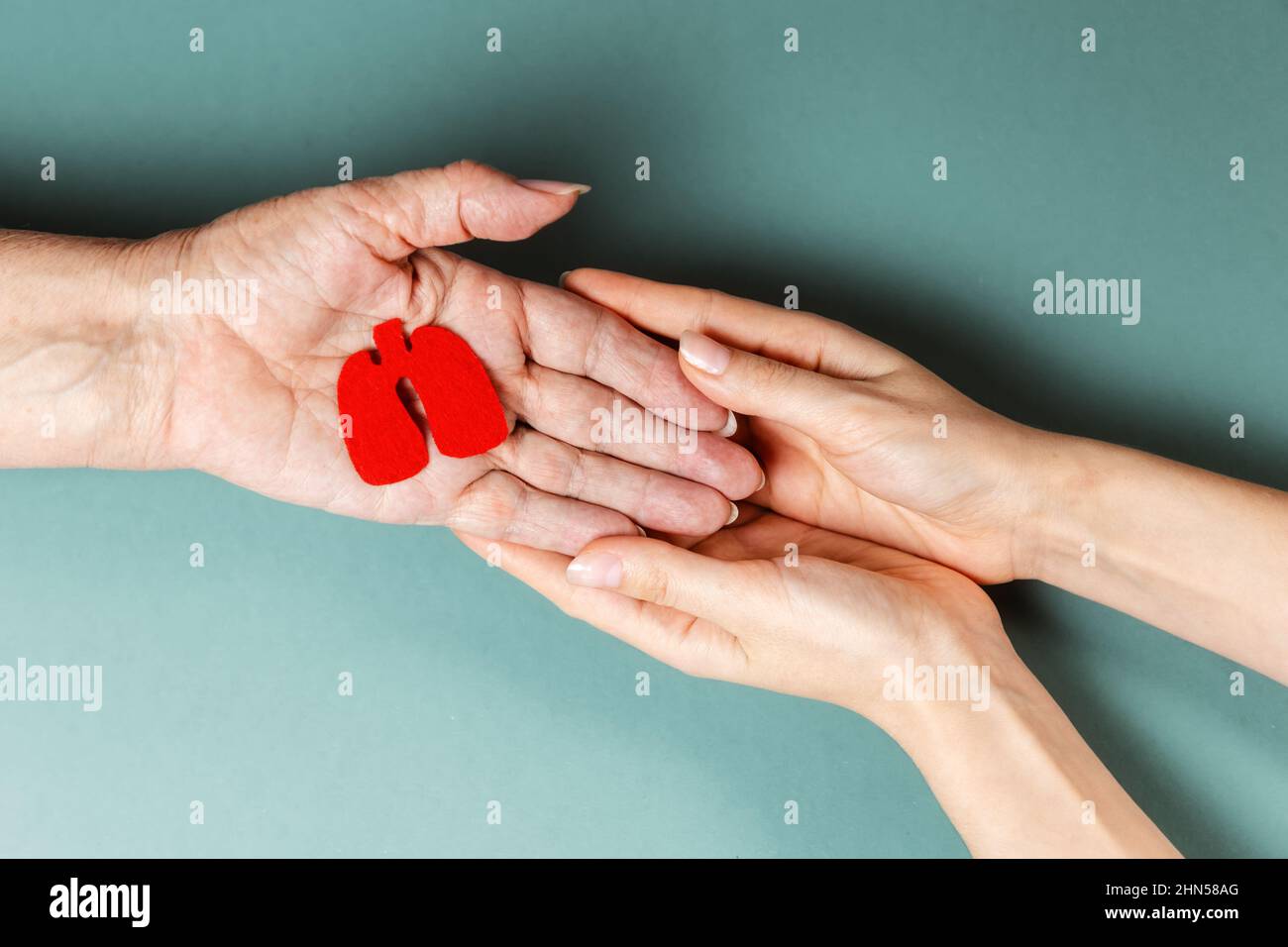 Young female hands hold an elderly hand showing a cut-out silhouette of ...