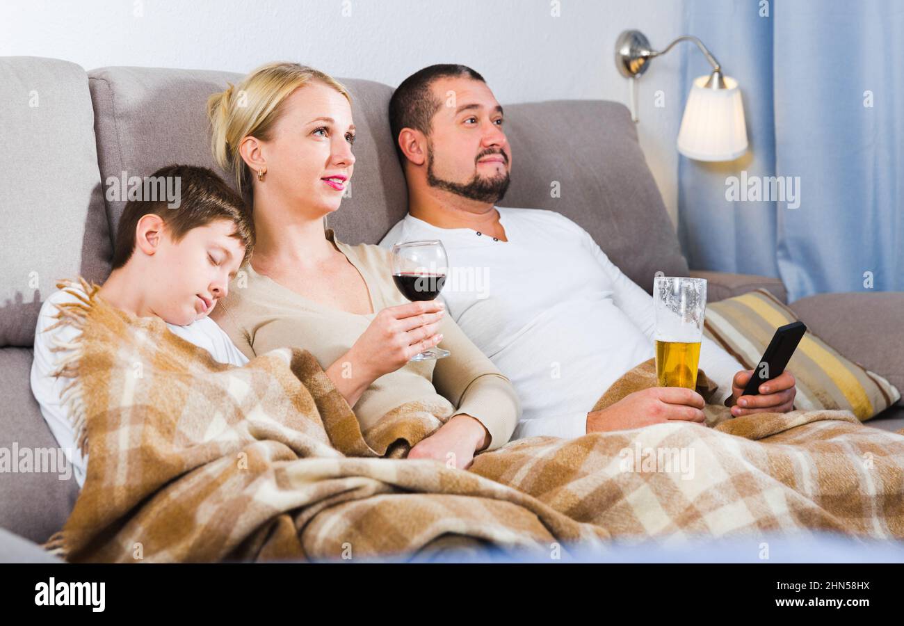 Happy parents with sleeping son watching TV Stock Photo - Alamy