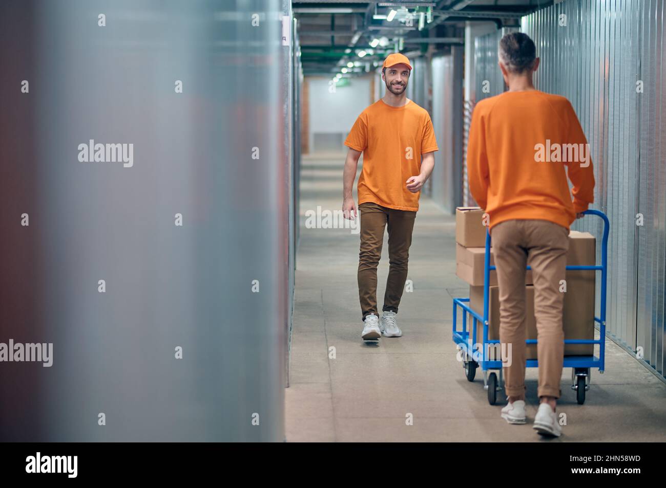 Joyous young man walking towards a warehouse loader Stock Photo - Alamy