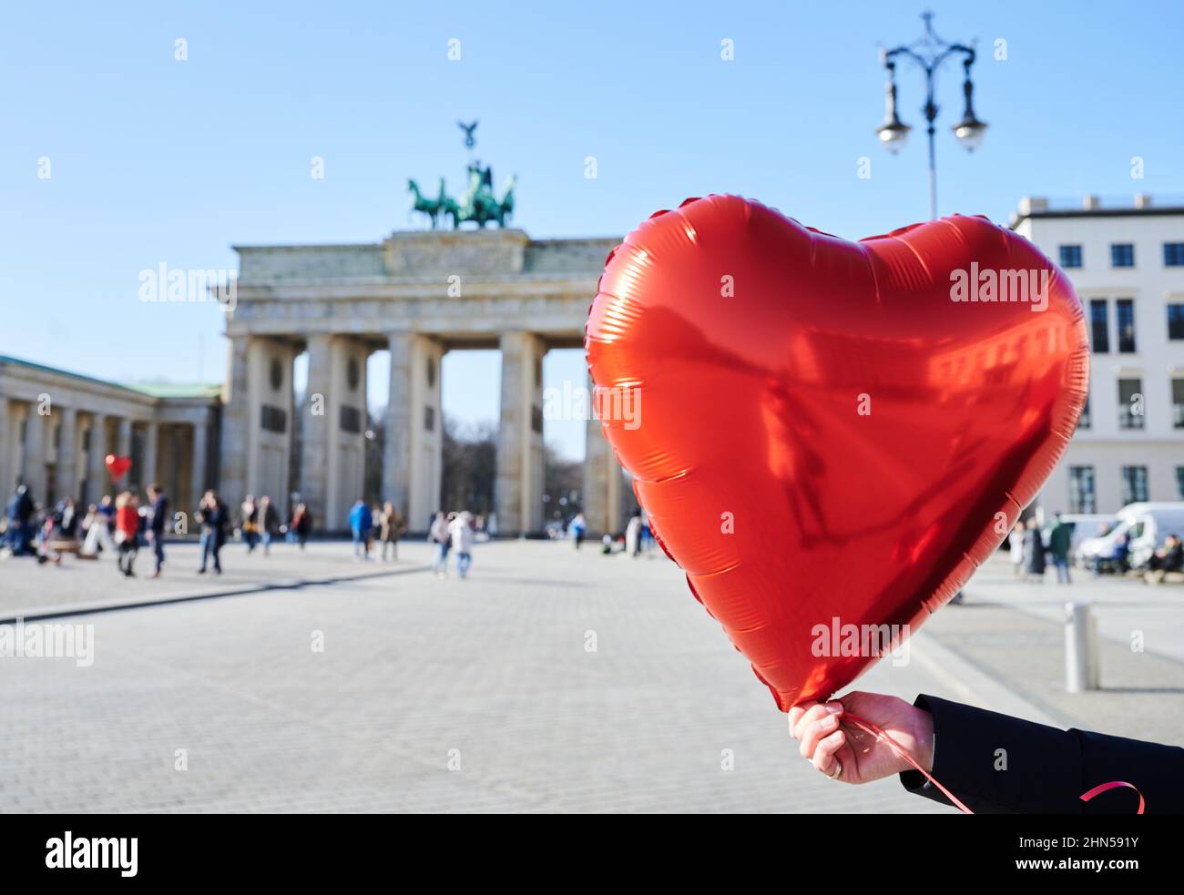 Berlin, Germany. 14th Feb, 2022. A woman holds a heart balloon in front ...