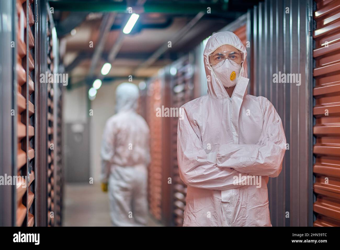Two warehouse employees wearing protective gear in the storage area ...