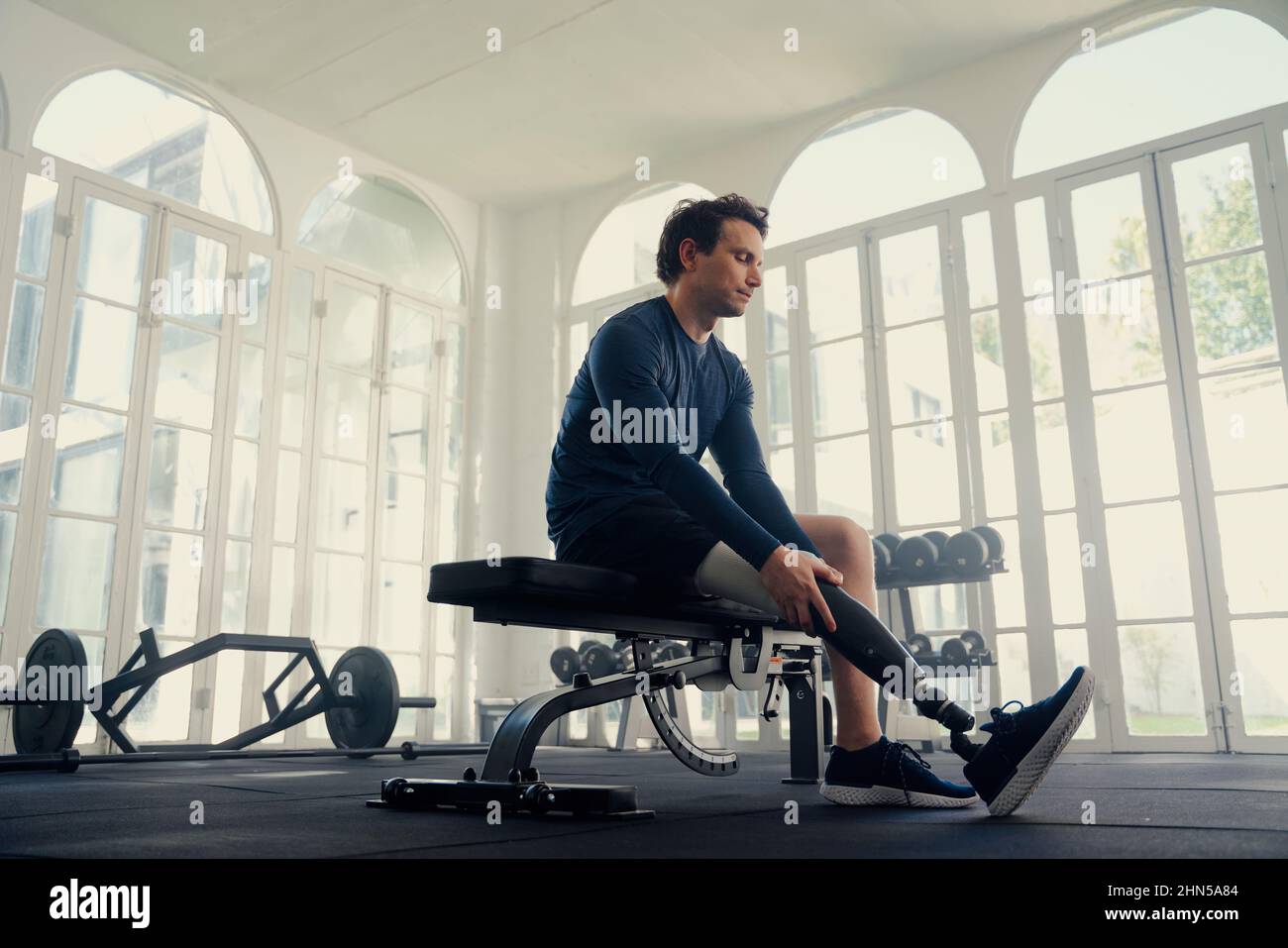 Wide shot of disabled male athlete putting on his prosthetic leg ...