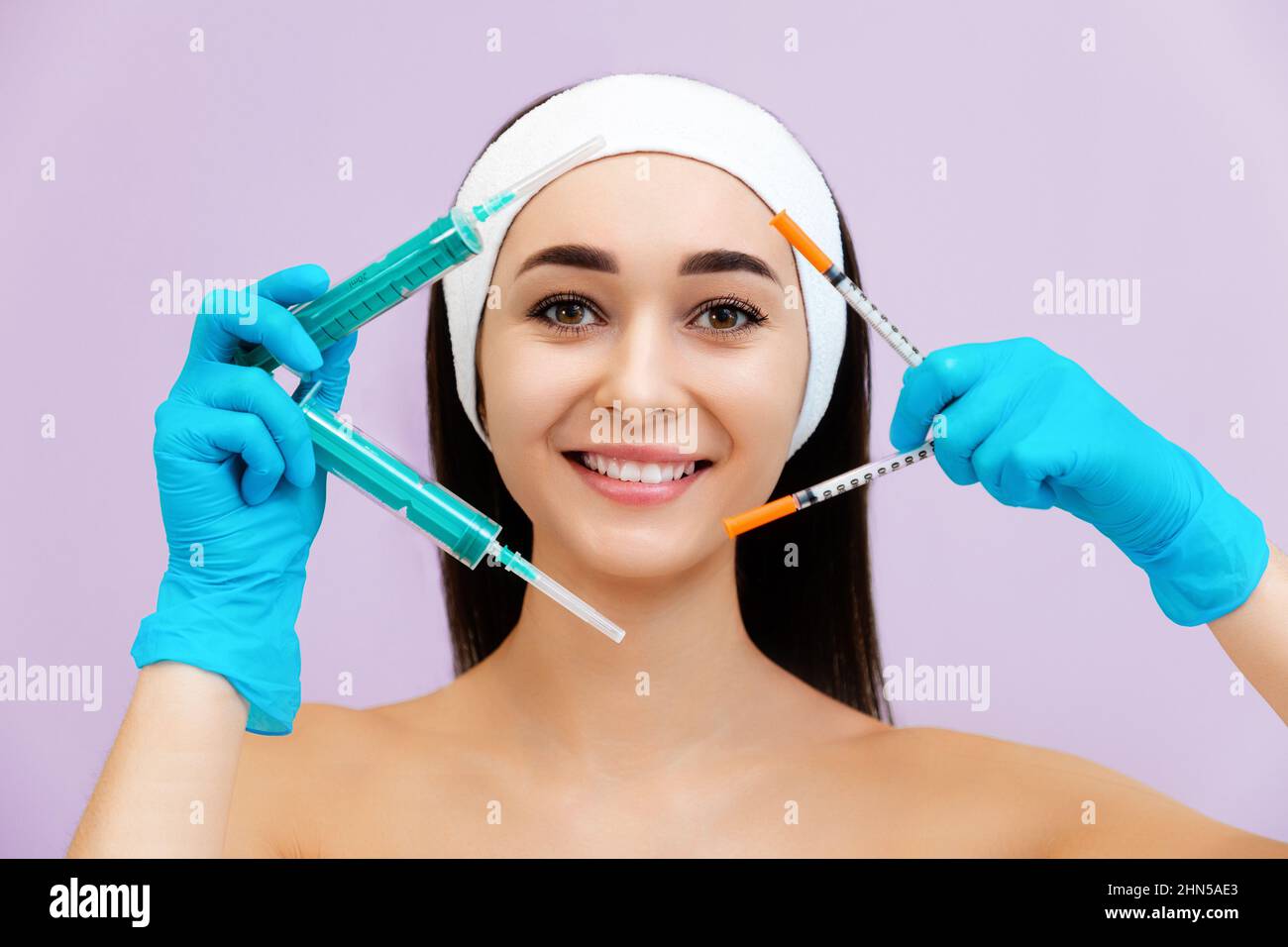 Portrait of a smiling attractive young woman holding syringes for ...