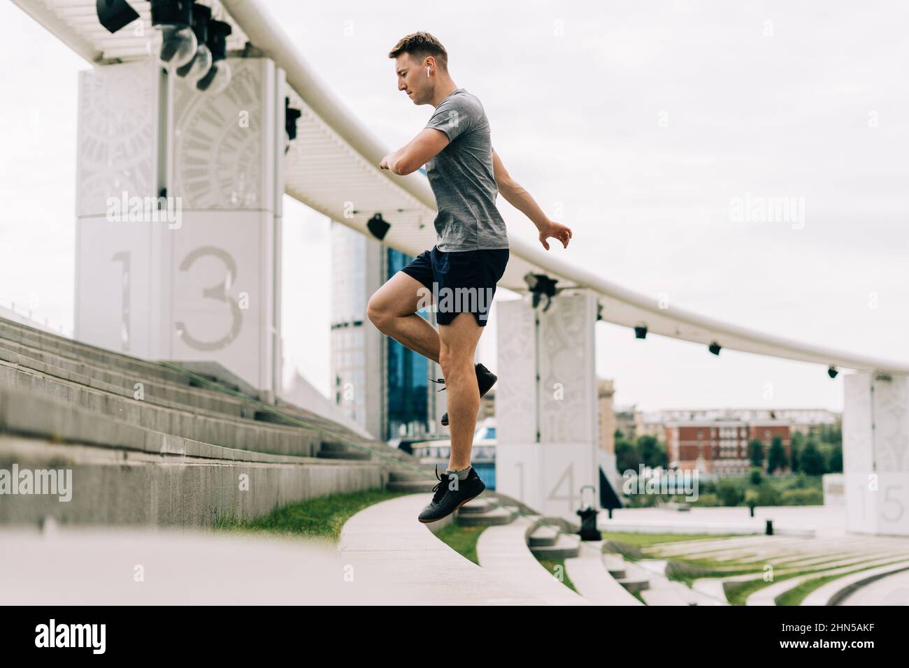 Young athlete man runner running up and down on city stairs in summer ...