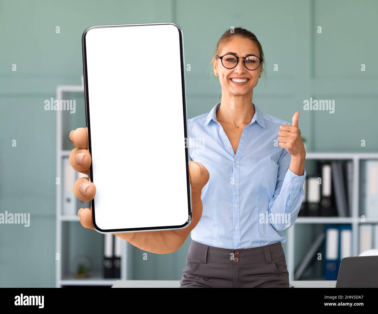 Attractive lady office manager showing smartphone with empty screen ...