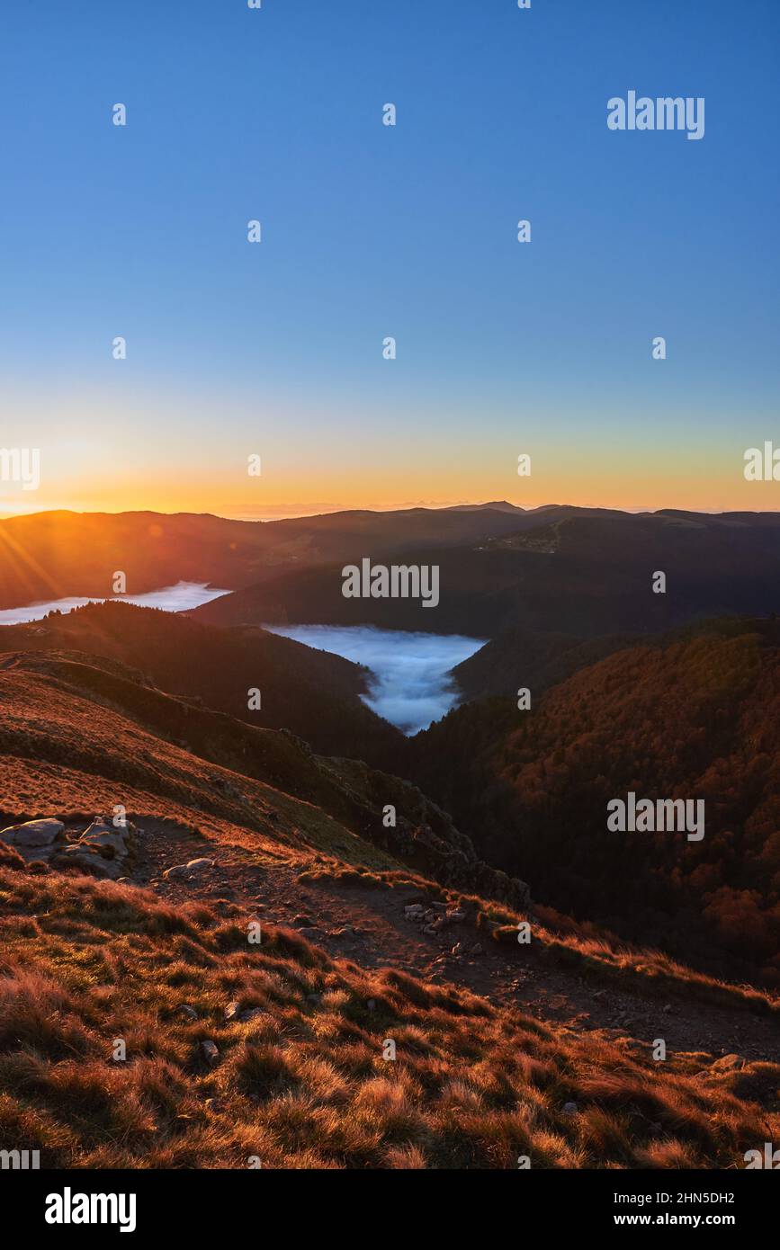 fog in between mountains with rising sun blue sky Stock Photo - Alamy