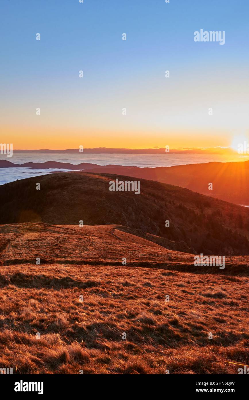 Sun rising on the horizon in a mountain landscape Stock Photo - Alamy