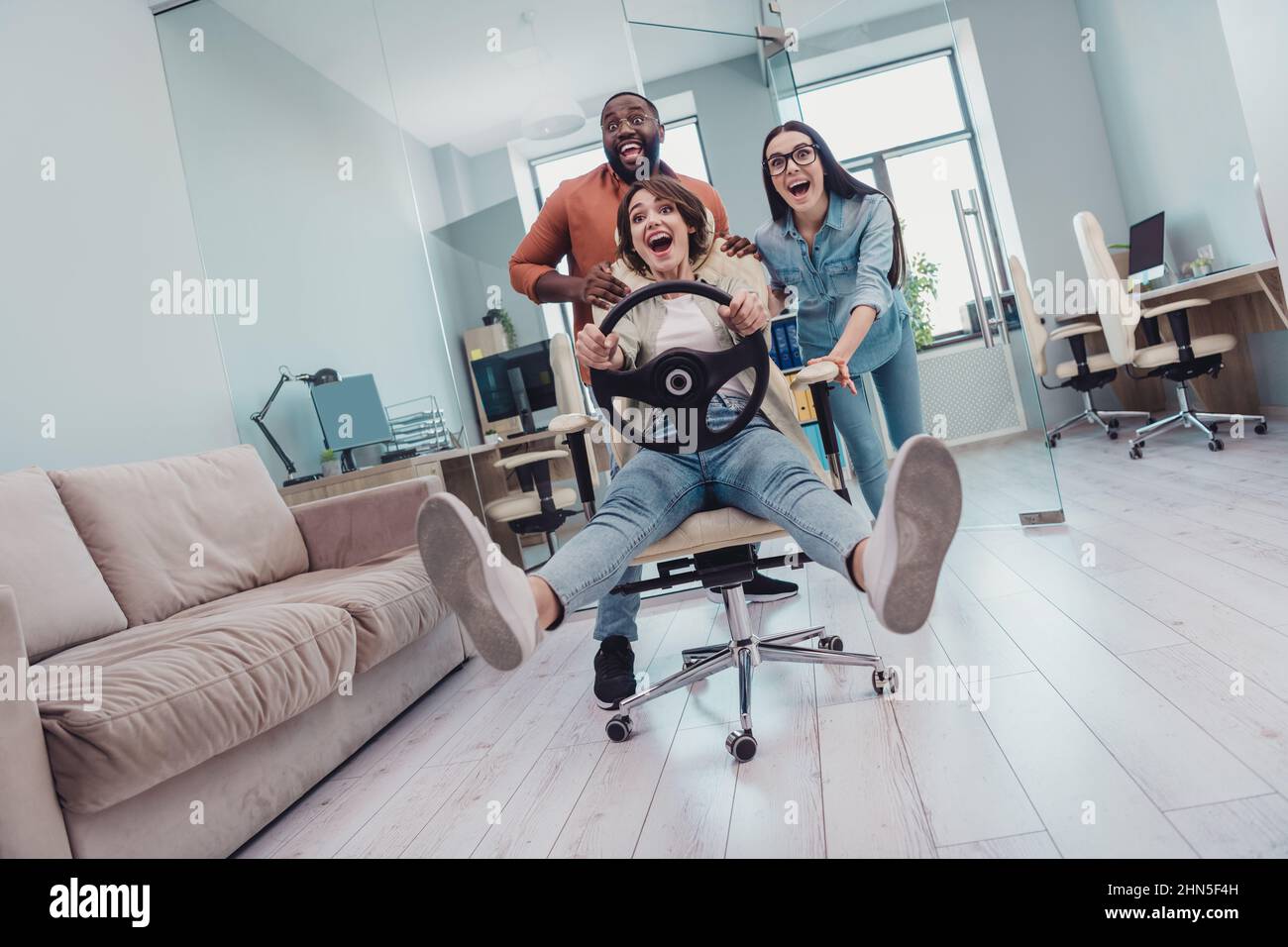 Portrait of attractive cheerful students having fun riding armchair ...
