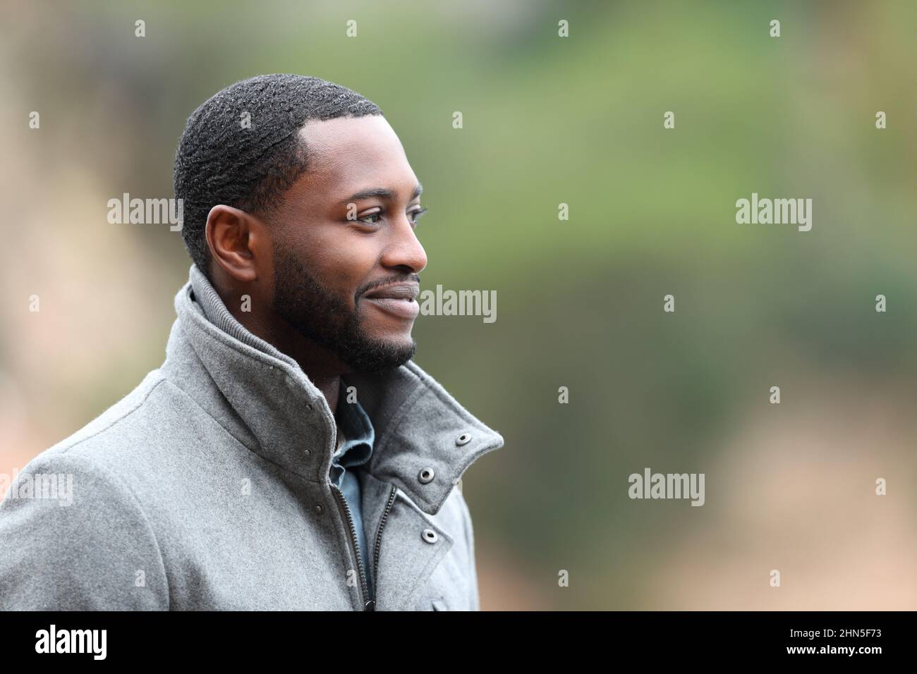 Satisfied man with black skin contemplating looking at side outdoors ...