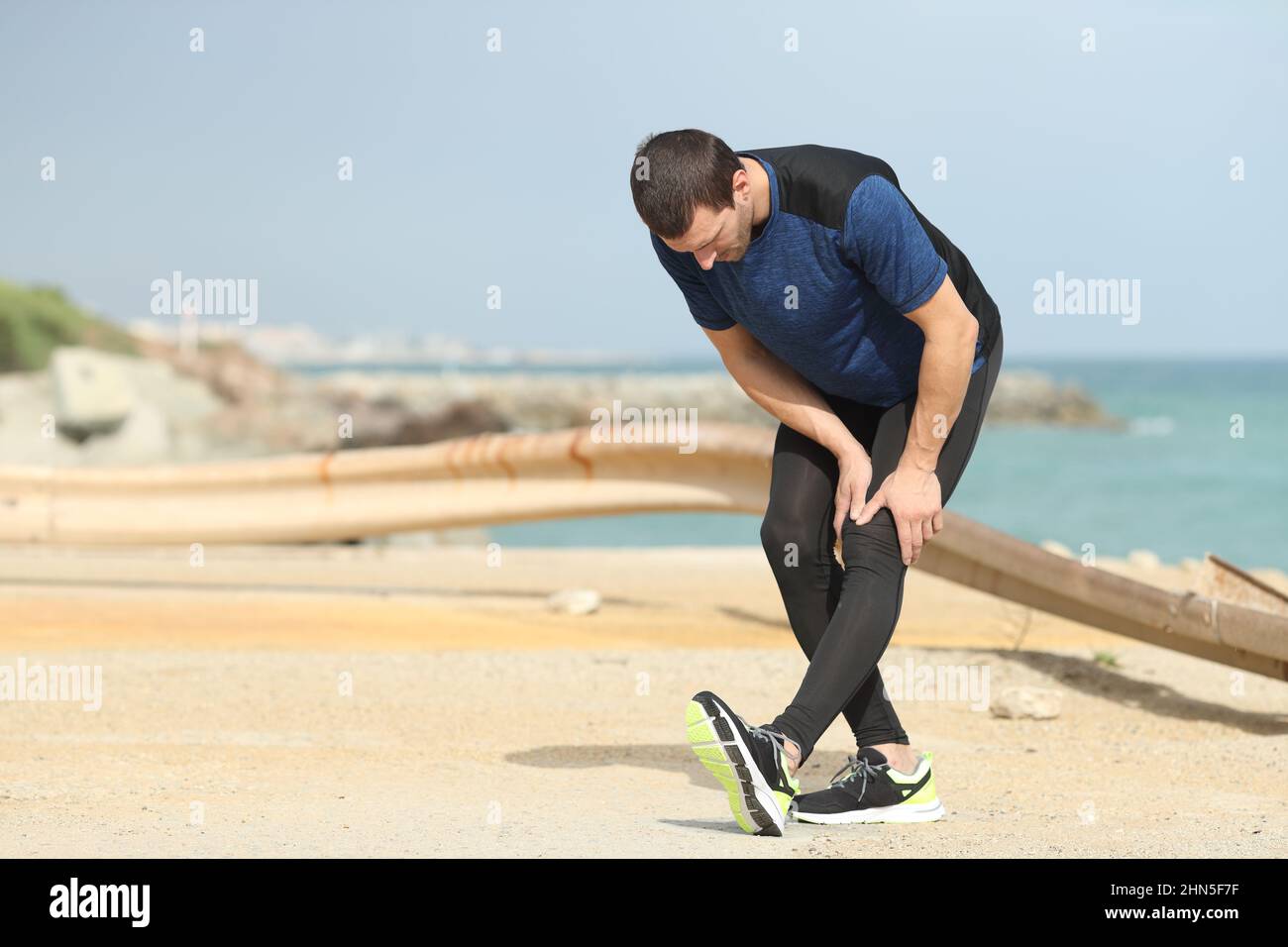 Runner stretching leg after sport on the beach Stock Photo - Alamy
